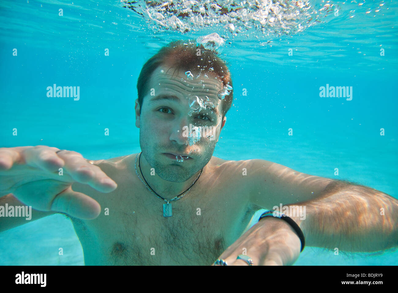 Young man swimming under surface in swimming pool Stock Photo - Alamy