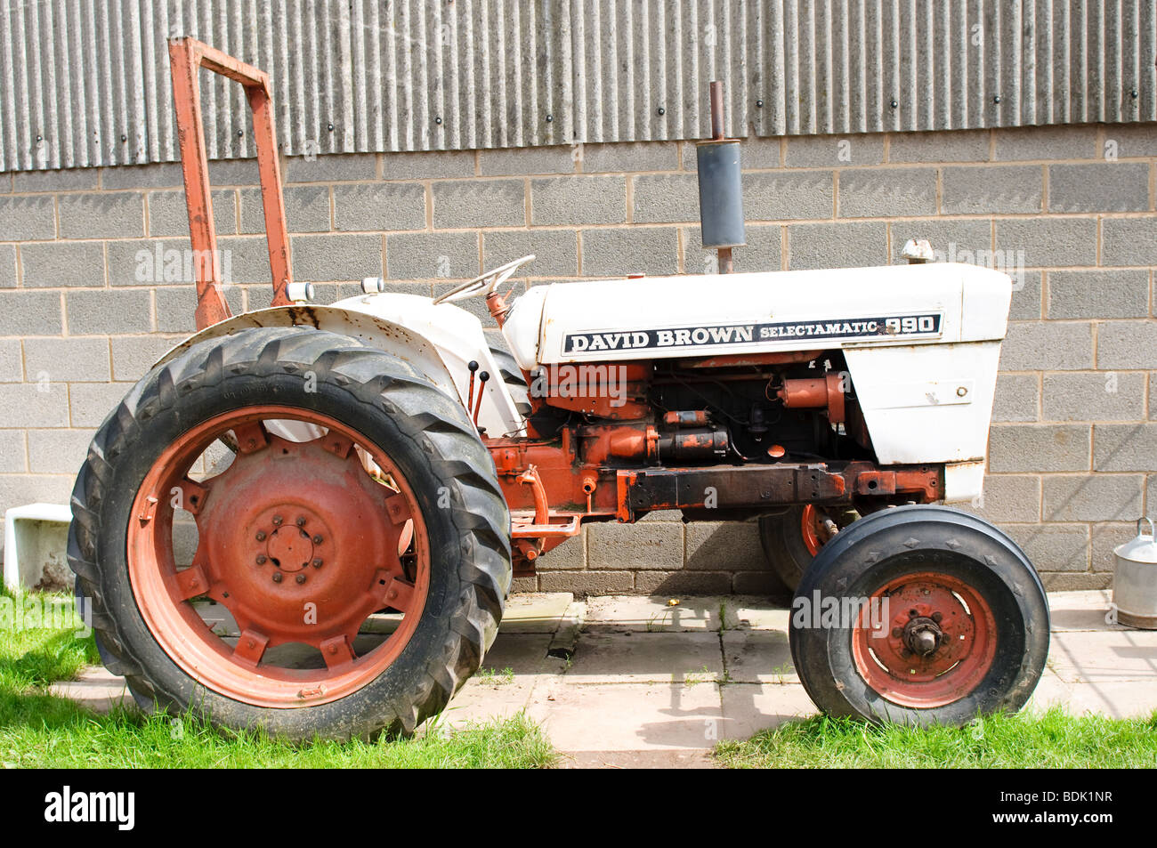 Profile View of red and white farm tractor against brick barn Stock ...