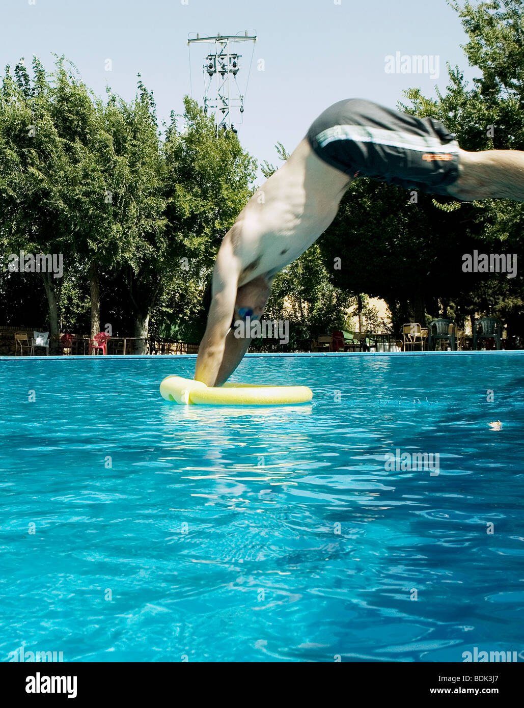man diving through inflatable hoop that is floating in a swimming pool ...