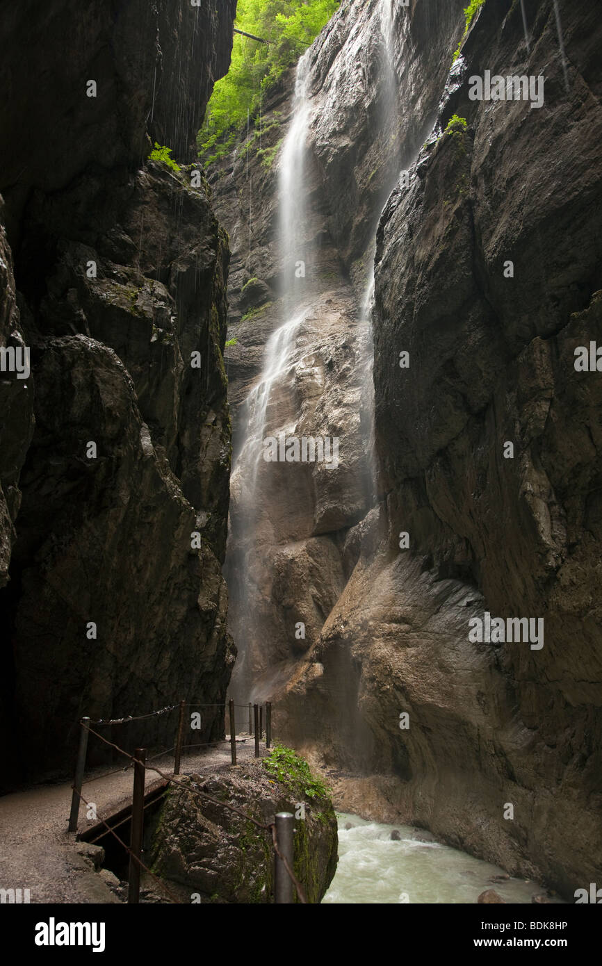 Beautiful tall waterfall against steep rock face in Partnachklamm gorge ...