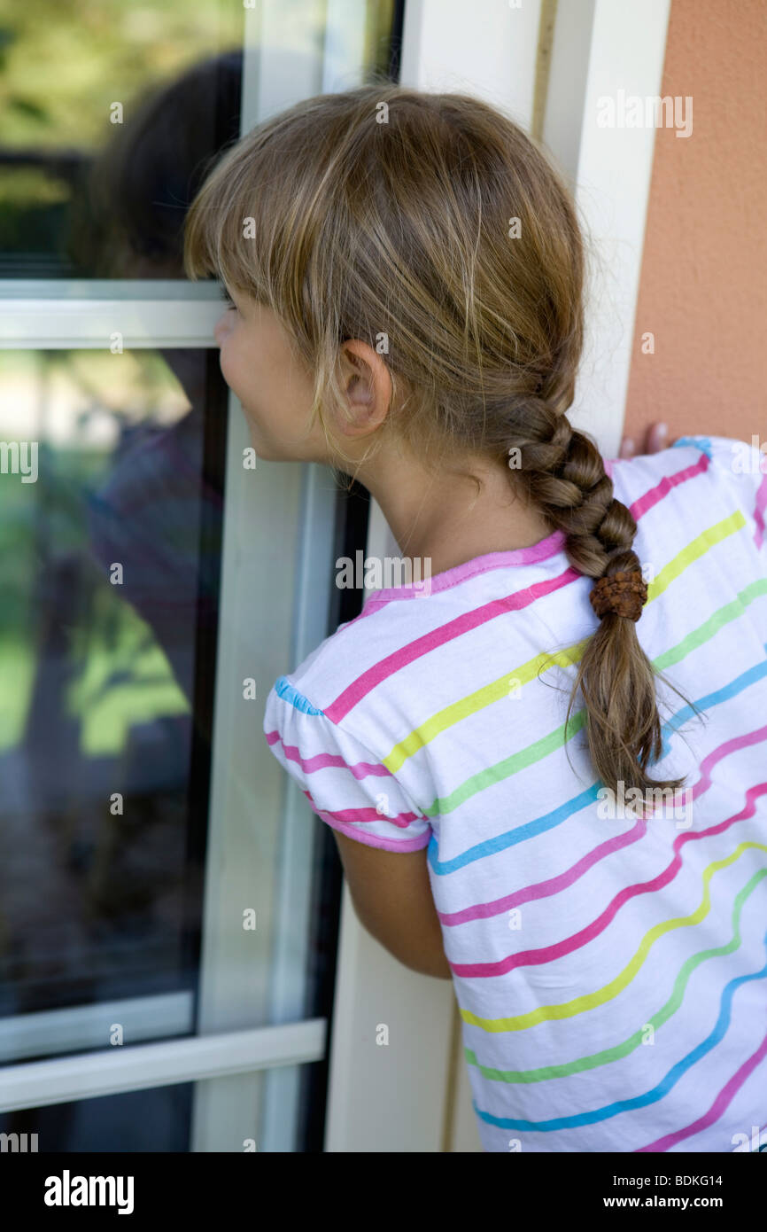 little girl eight years old look through window Stock Photo - Alamy