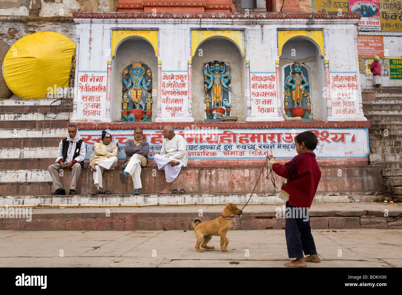 A group of four Indian men sits and chats on one of the ghats by the ...