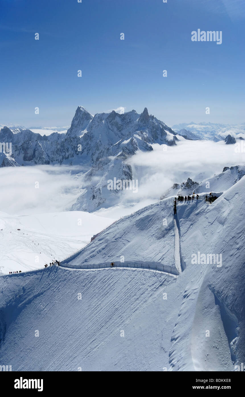 Snow slope with paths against blue sky, white clouds and steep peaks ...
