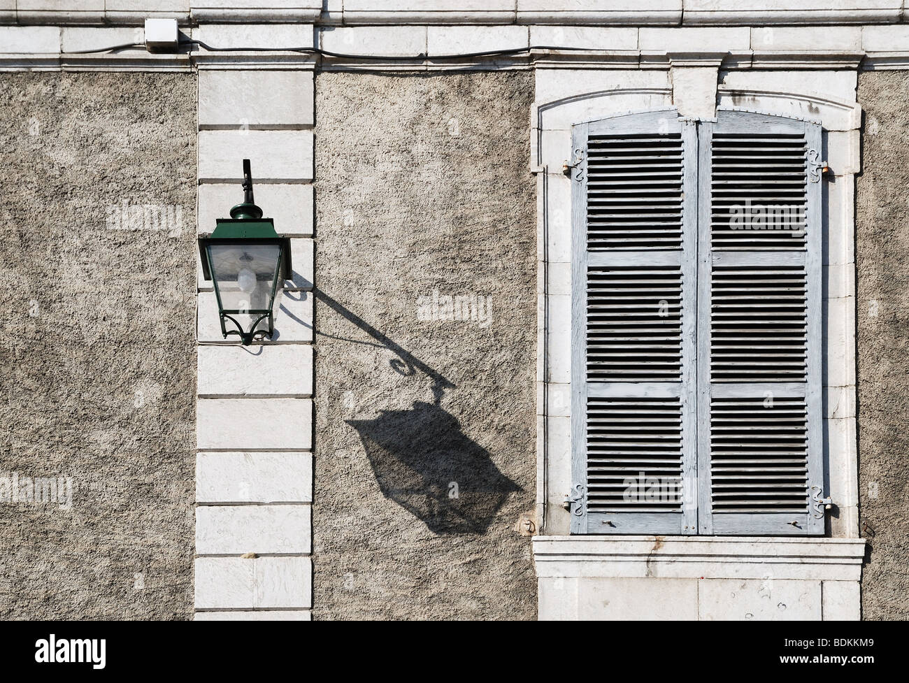 Dark shadow of lantern crawls on sunlit wall to window closed with ...