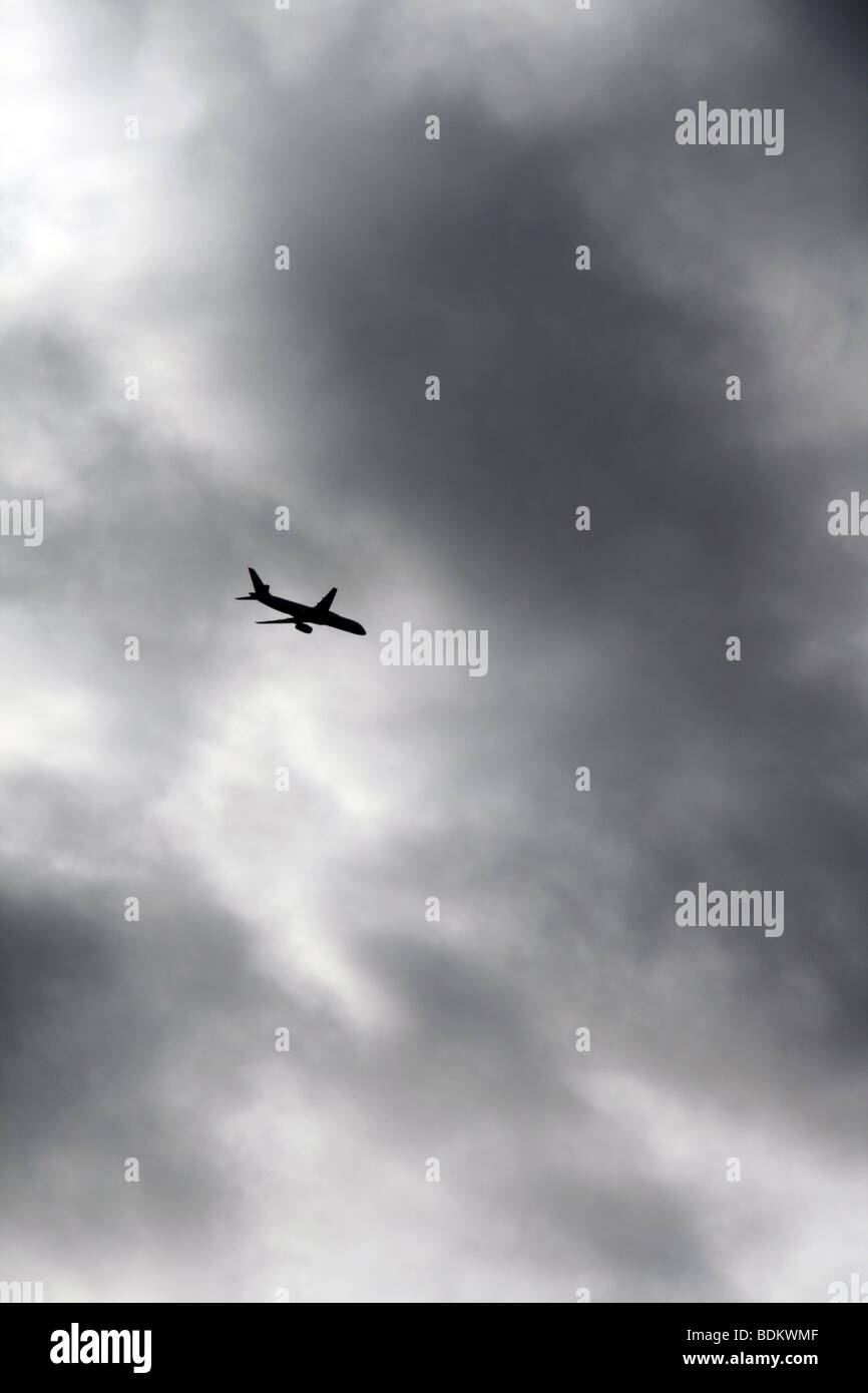 plane flying through dark clouds in sky Stock Photo - Alamy