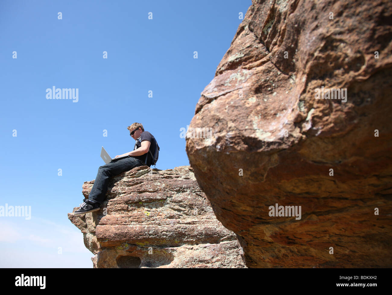 Young man using laptop on cliff Stock Photo - Alamy