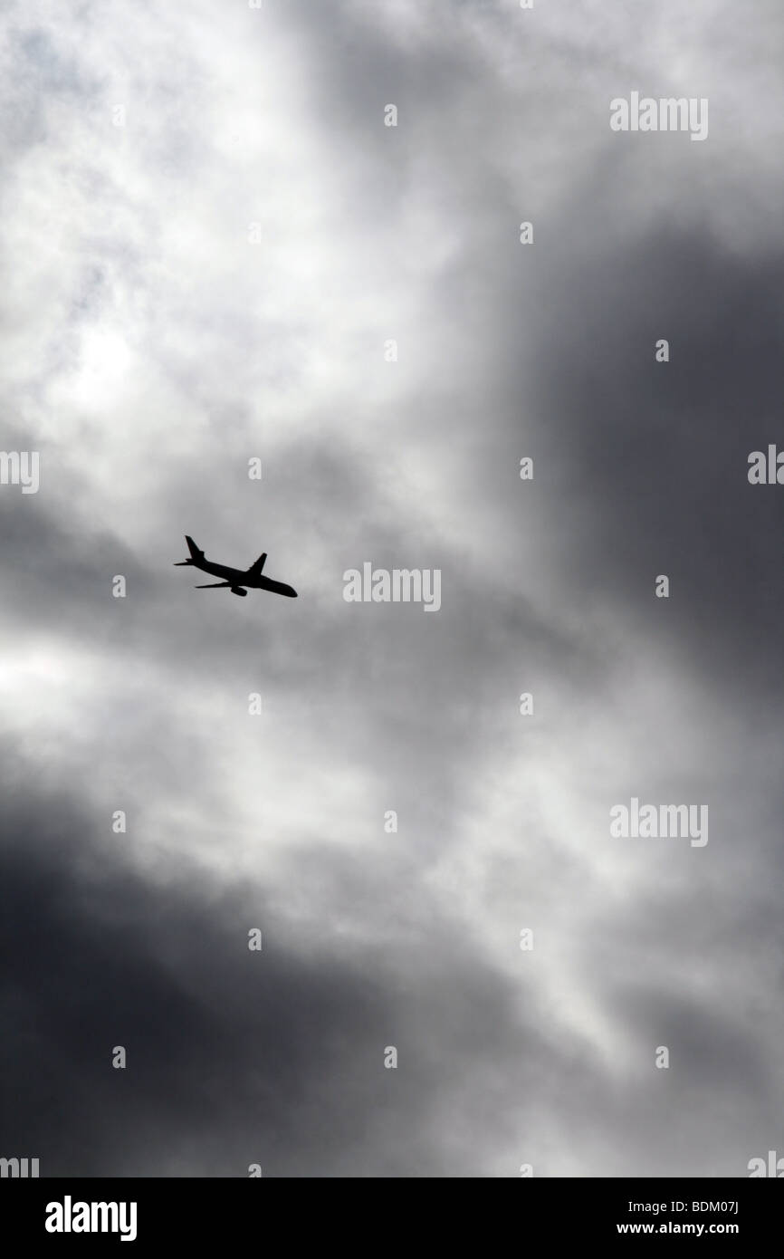 plane flying through dark clouds in sky Stock Photo - Alamy