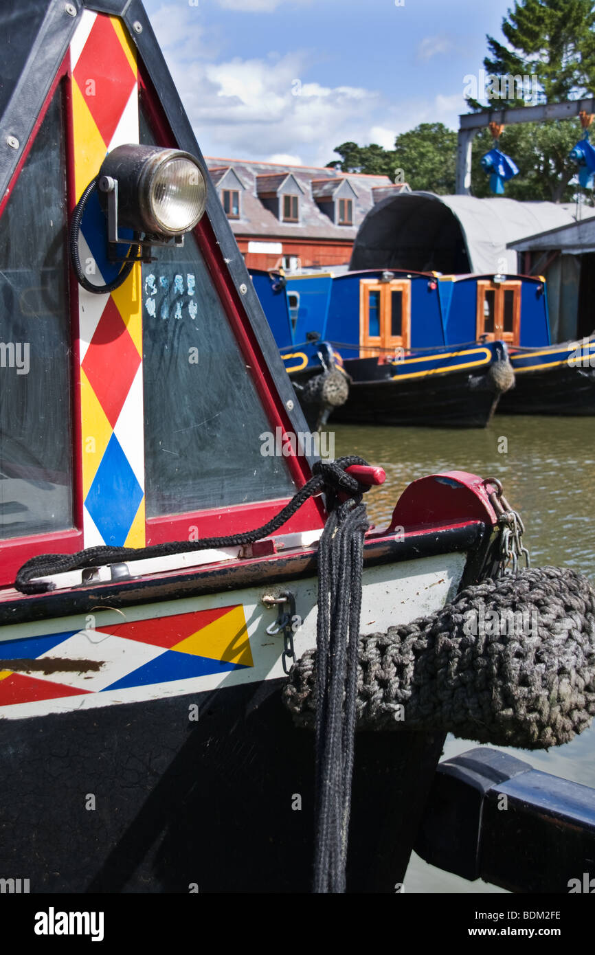 Brightly coloured narrow boat, in front of 3 blue narrowboats with a ...