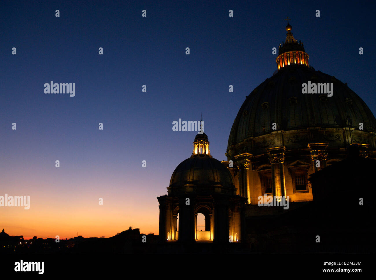 The domes of Saint Peters Basilica illuminated against a golden sunset ...