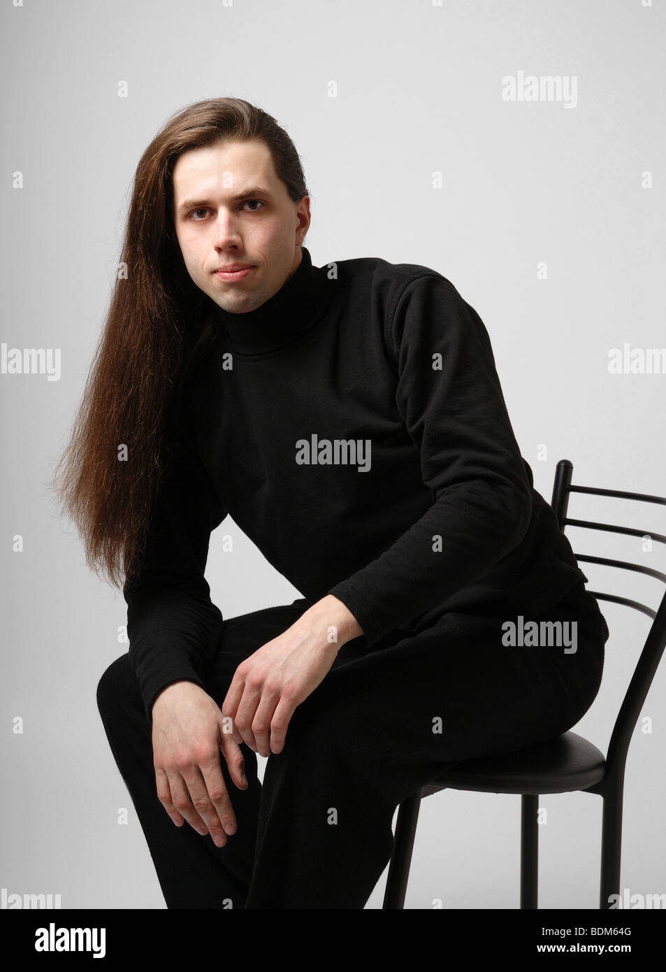 Well-grown fellow sitting in black sweater and trousers Stock Photo - Alamy