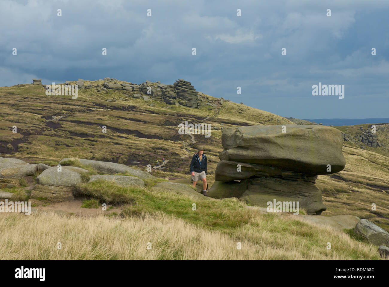 Walker passing the Noe Stool on Kinder Scout, near Edale, Peak National ...