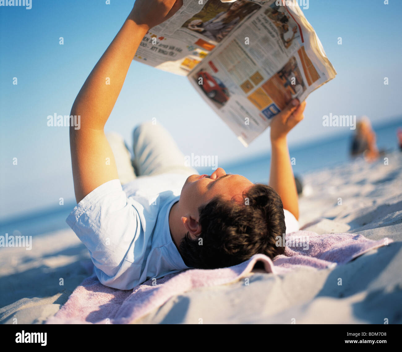 Man reading a newspaper on the beach Stock Photo - Alamy