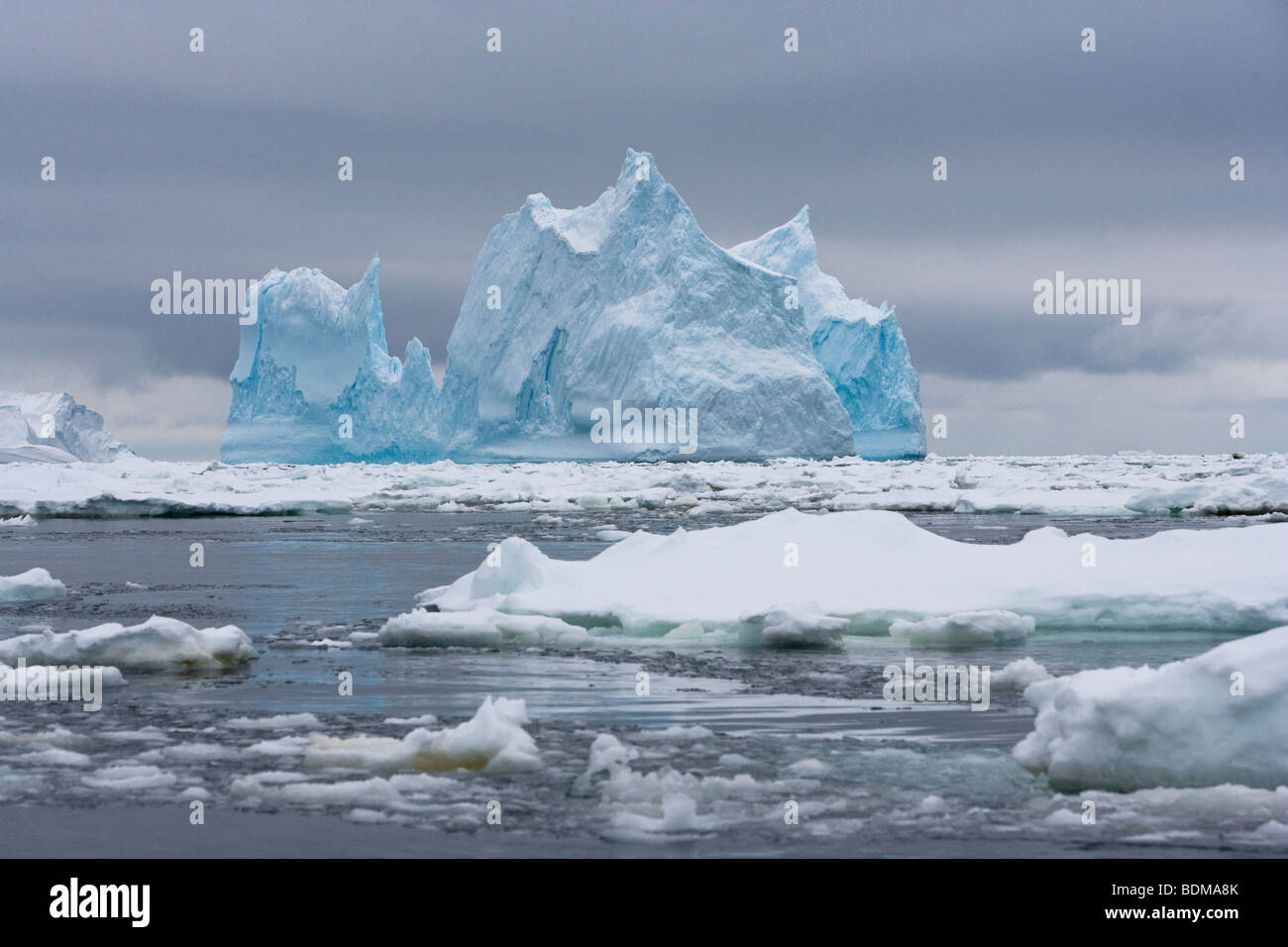 Big blue iceberg, floating in ice floe with chunks of broken sea ice ...