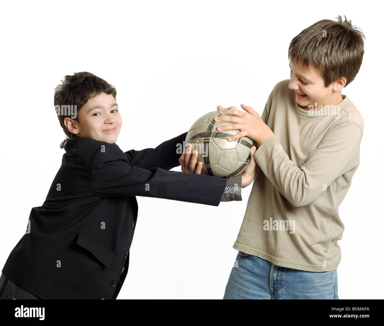 Two preteen boys pull out ball with each other. Side view. The children ...