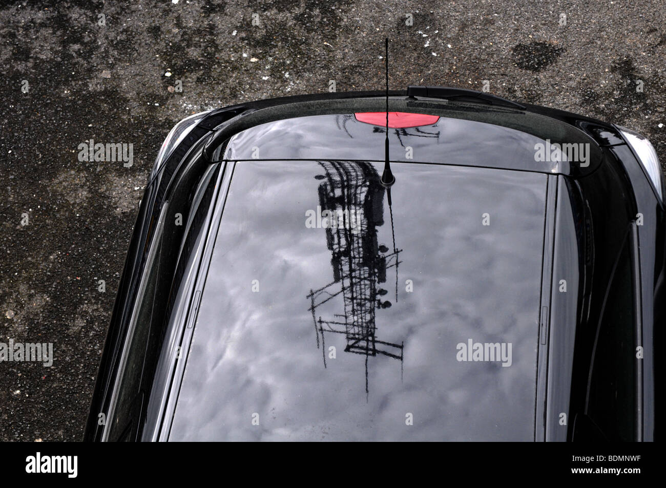 Reflection of a telecommunication tower on the roof of a black car with ...