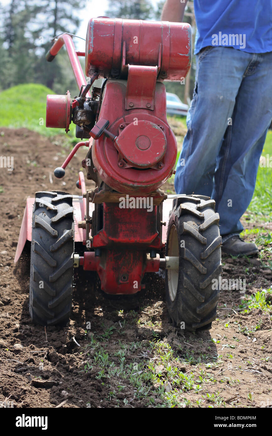 Man rototilling the ground, getting it ready for a garden. Close-up of ...