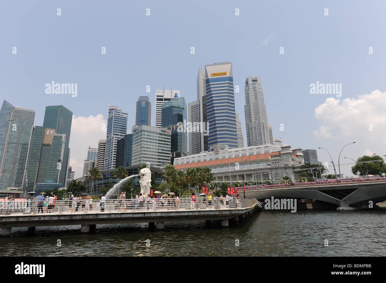 tourists at Merlion Park with Fullerton Hotel and city skyline ...