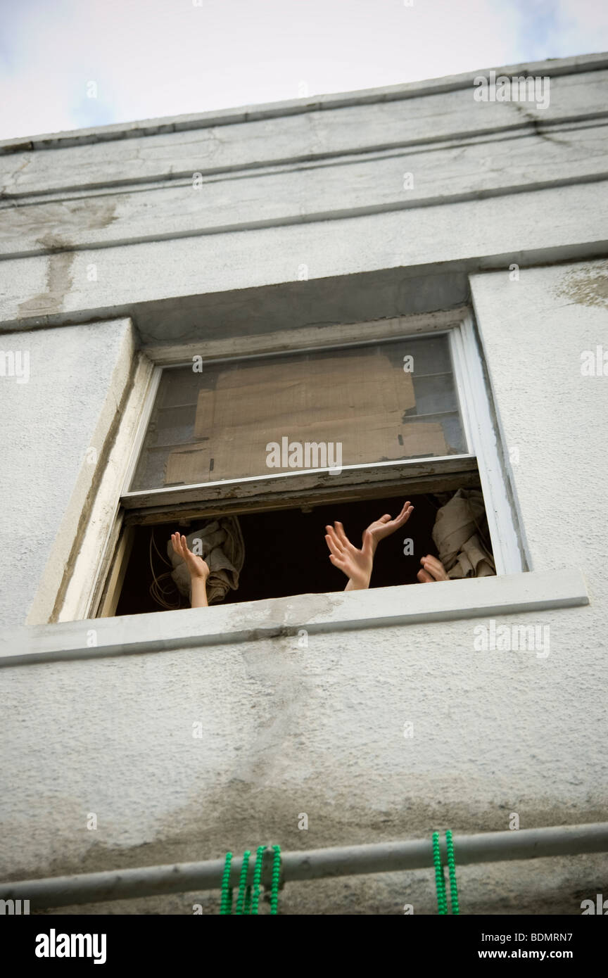 Hands and arms seen coming out of an upstairs window wait to catch ...
