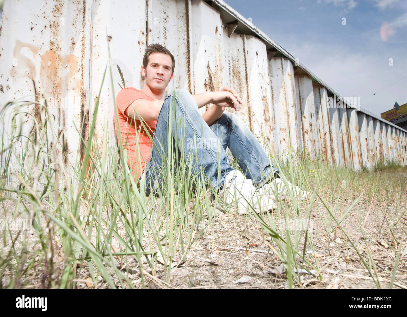 Young man sitting in front of a wall Stock Photo - Alamy