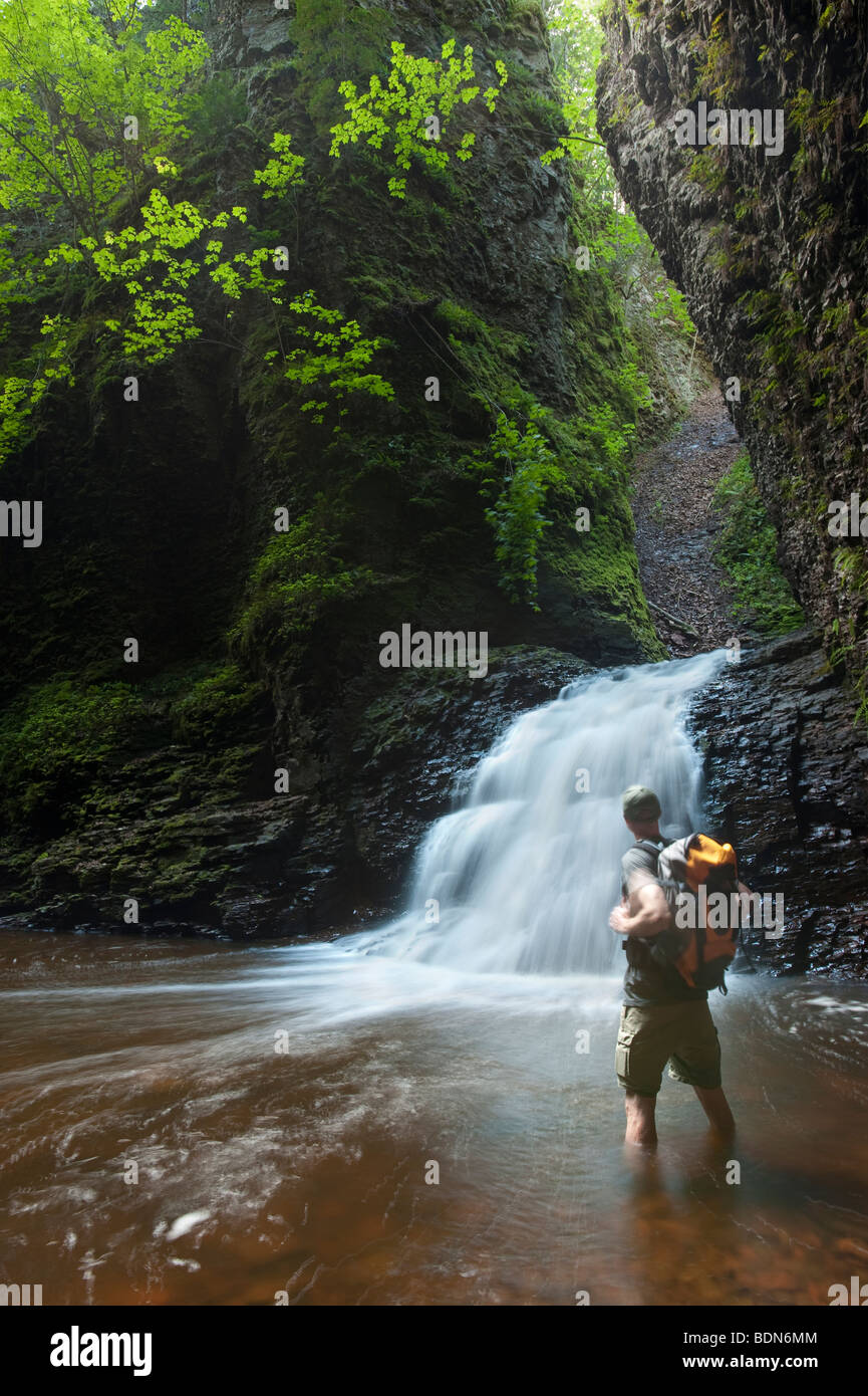 A BACKPACKER STANDS IN A SHALLOW POOL IN FRONT OF A WATERFALL Stock ...