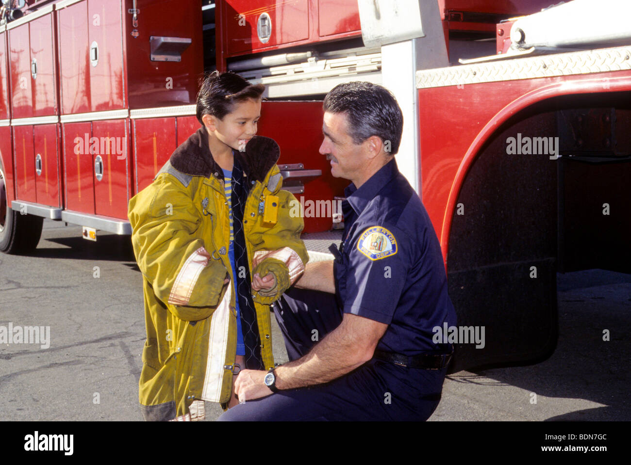 Latin kid talks to firefighter at fair show show demonstrate teach ...