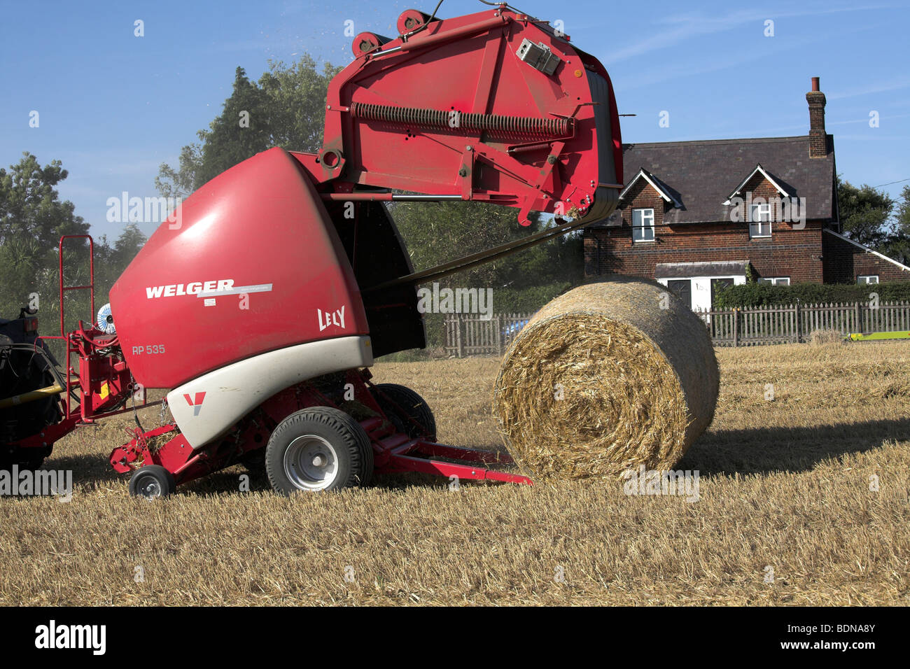 Straw baler working in a field Stock Photo - Alamy