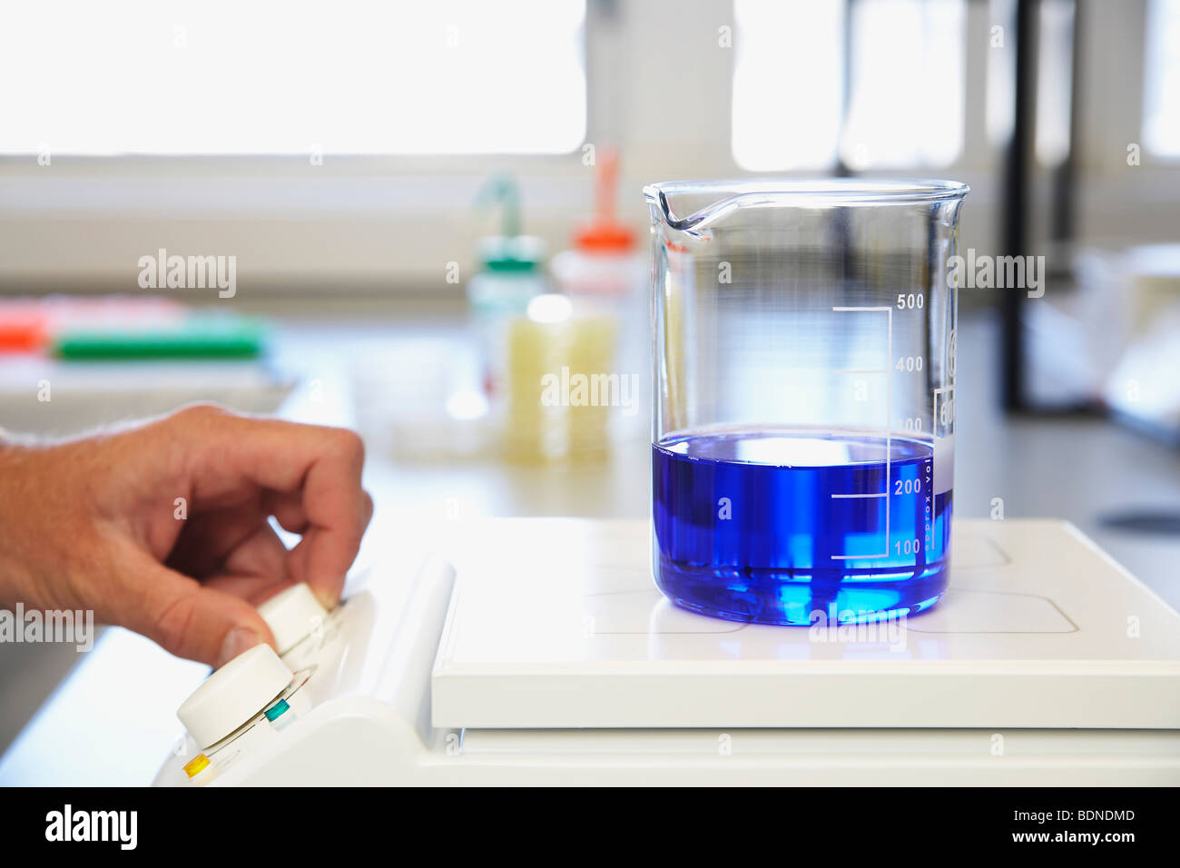 Scientific glass container with blue liquid on apparatus, being ...