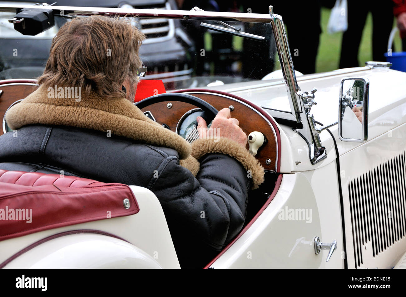 Driver in a flying jacket behind the wheel of a vintage sports car ...