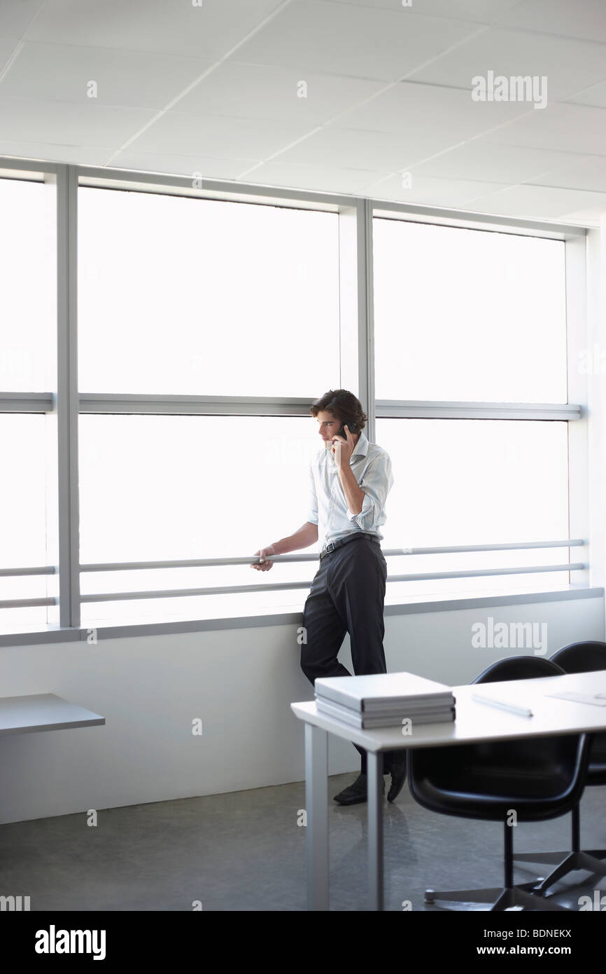 Business man using mobile phone looking out of office window Stock ...