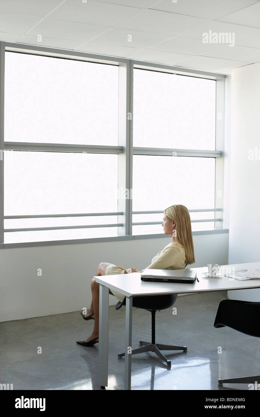 Business woman looking through window sitting in office Stock Photo - Alamy