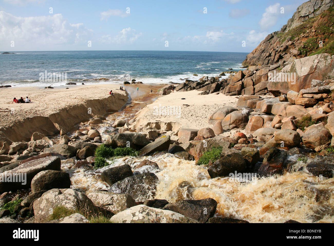 People relaxing on the beach of a sandy cove on the rocky coast near ...