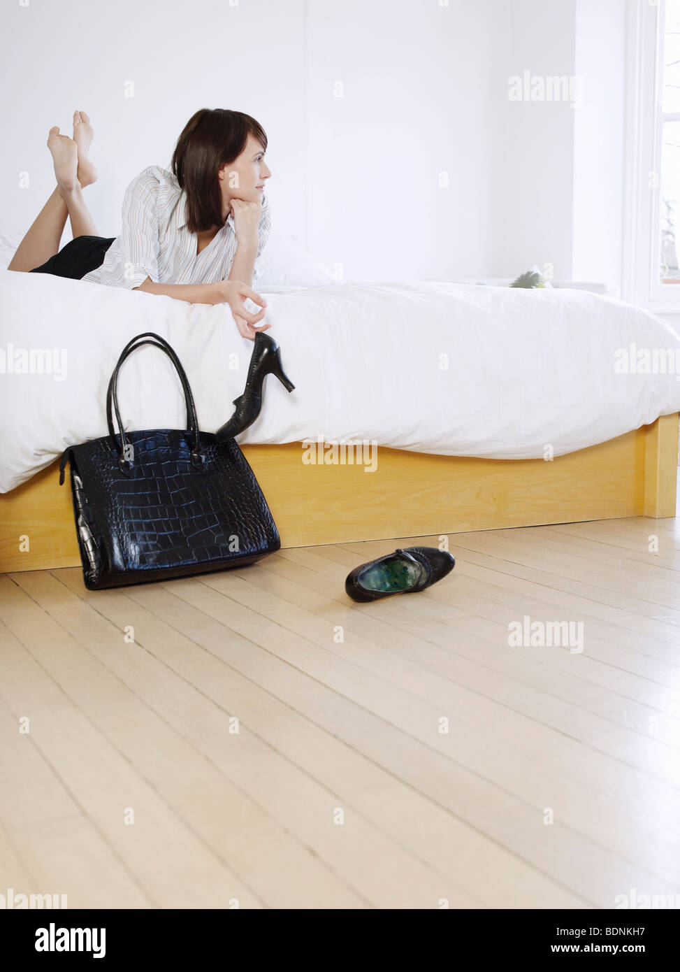 Young woman lying on bed, holding one high heeled shoe Stock Photo - Alamy