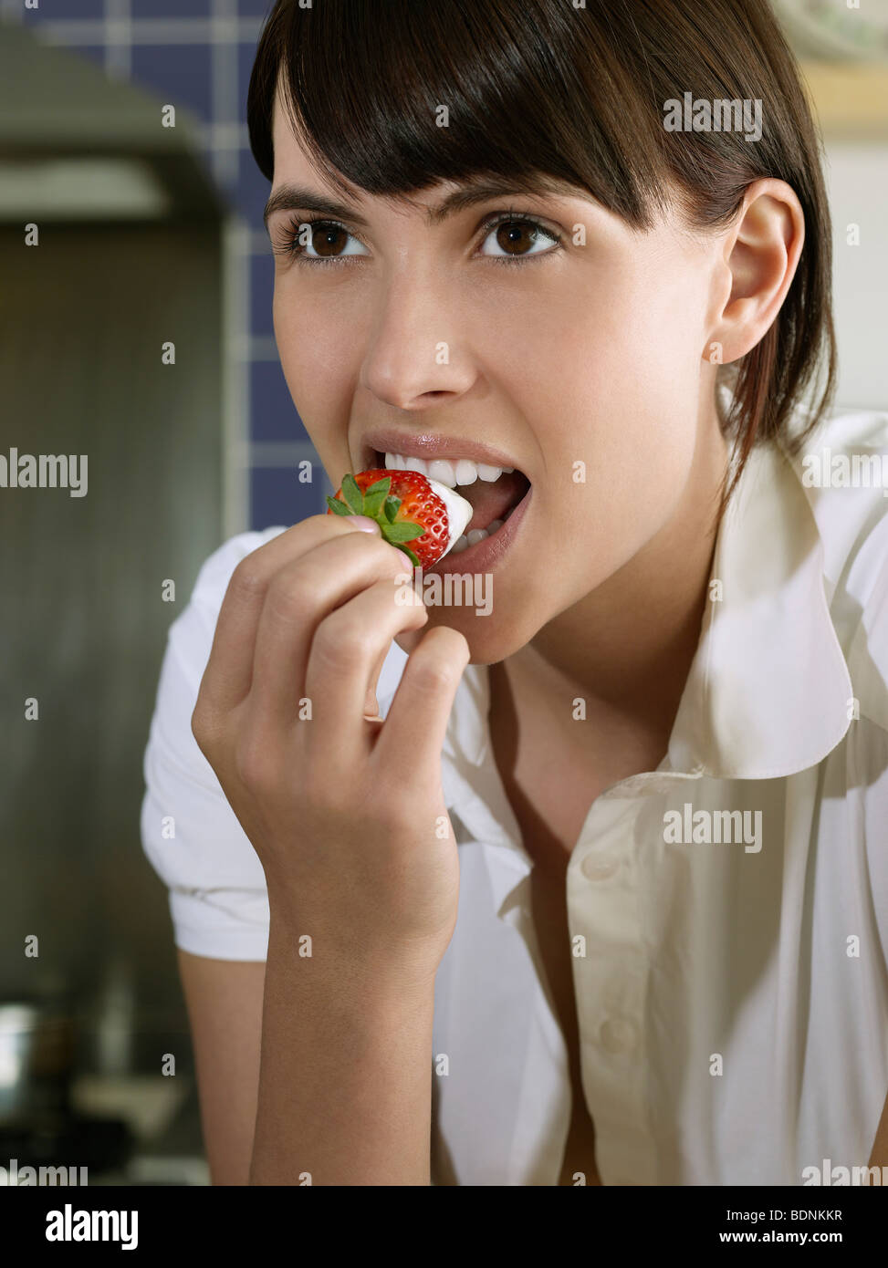 Young woman biting strawberry Stock Photo - Alamy