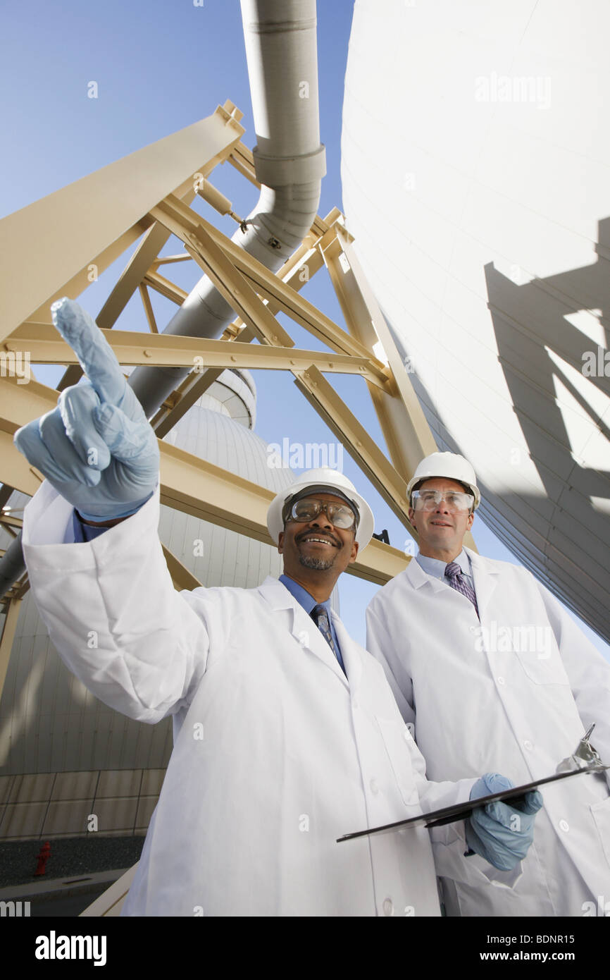 Scientist pointing forward with another scientist standing beside him ...