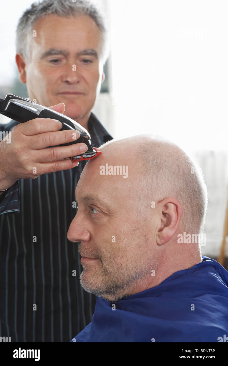 Barber shaving mans head in barber shop Stock Photo - Alamy