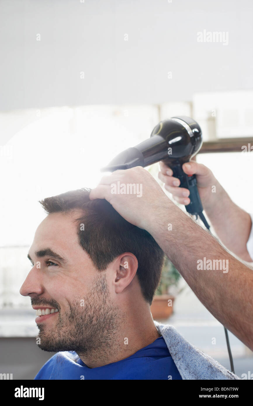 Barber drying mans hair in barber shop Stock Photo - Alamy
