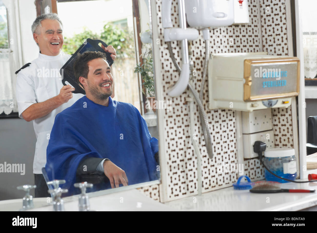 Barber showing man hair in mirror, at barber shop Stock Photo - Alamy