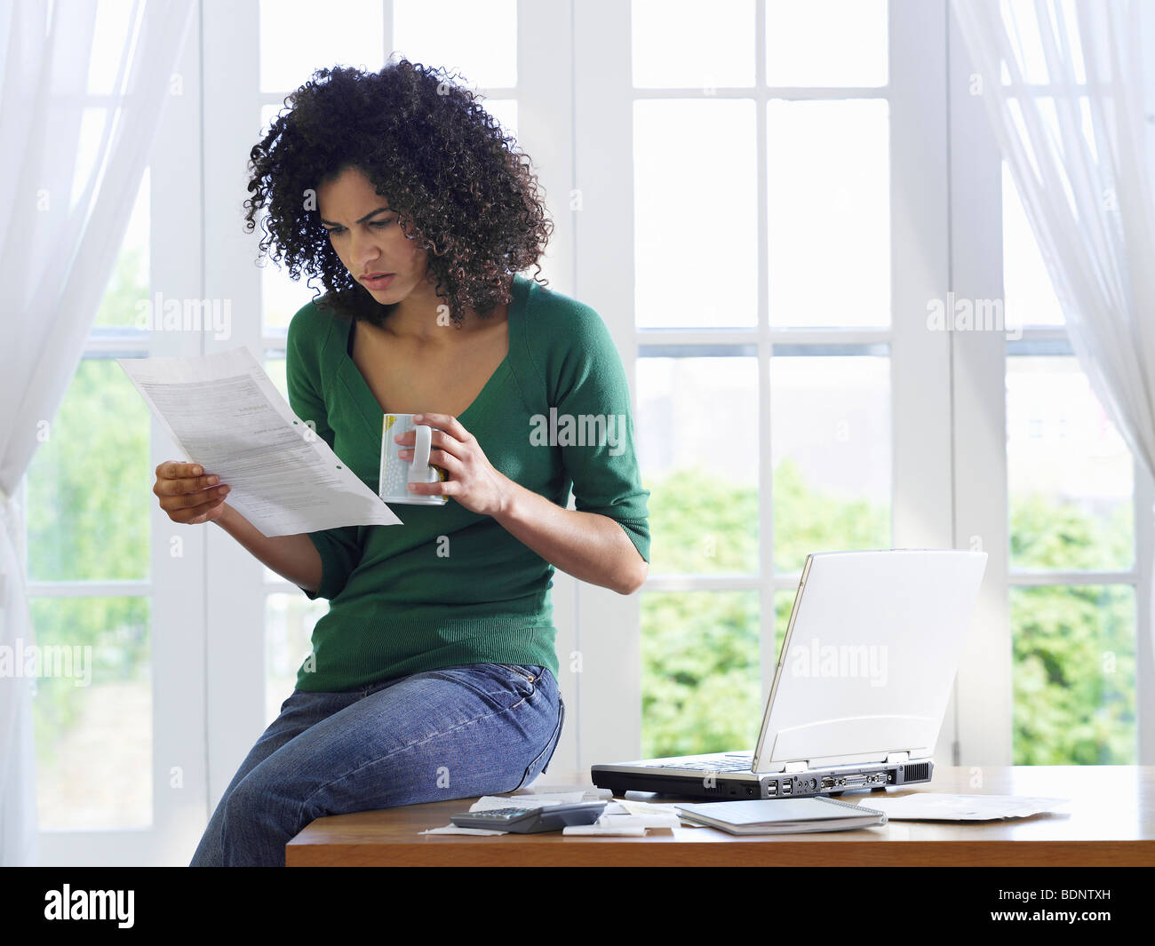 Woman reading paper document, sitting on desk Stock Photo - Alamy