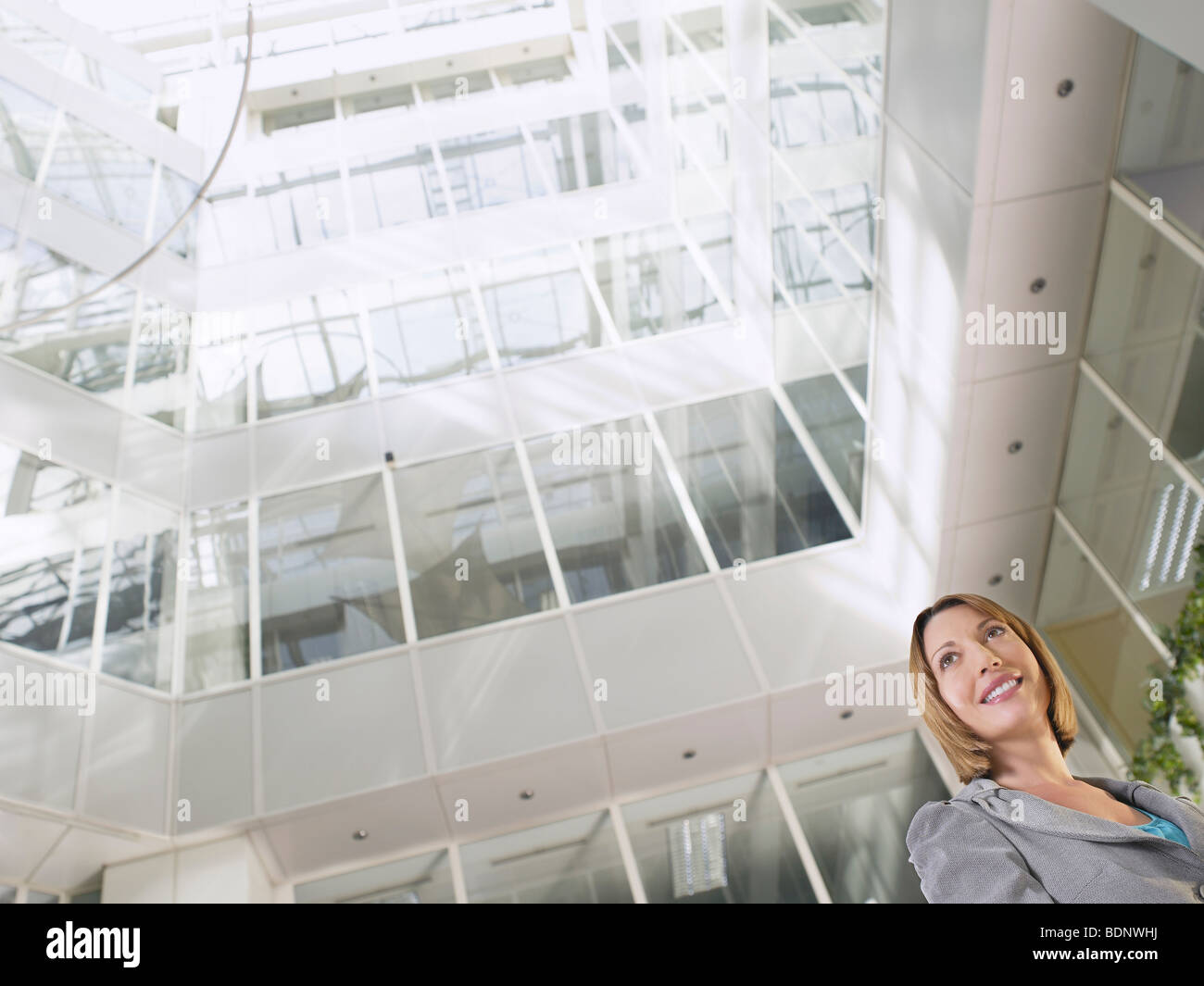 Business woman standing in atrium of office building, low angle view ...