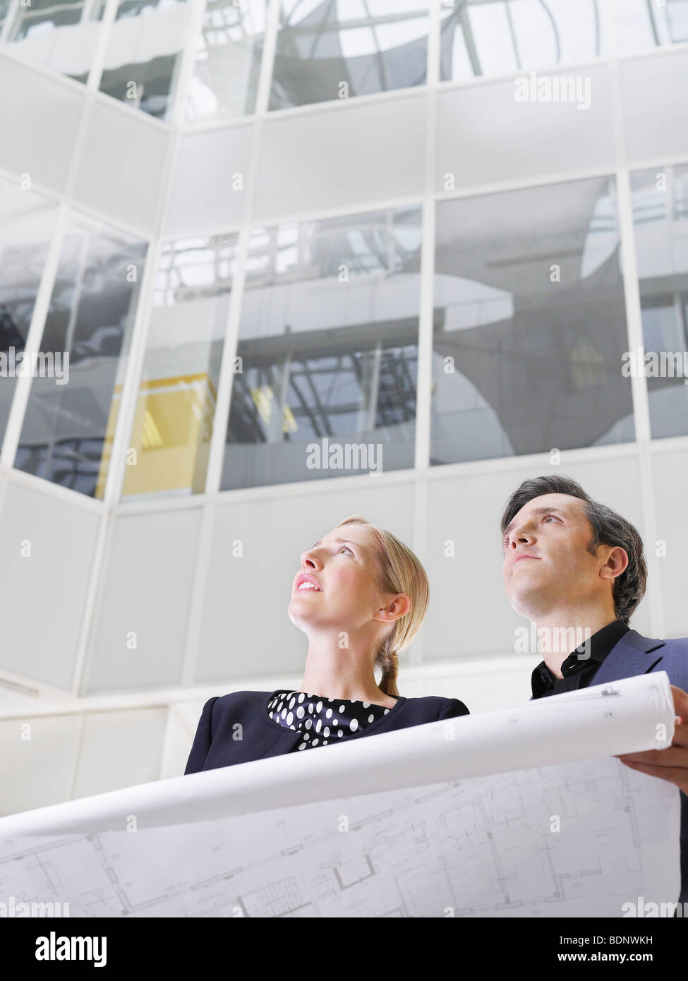 Two business people holding blueprint, low angle view Stock Photo - Alamy