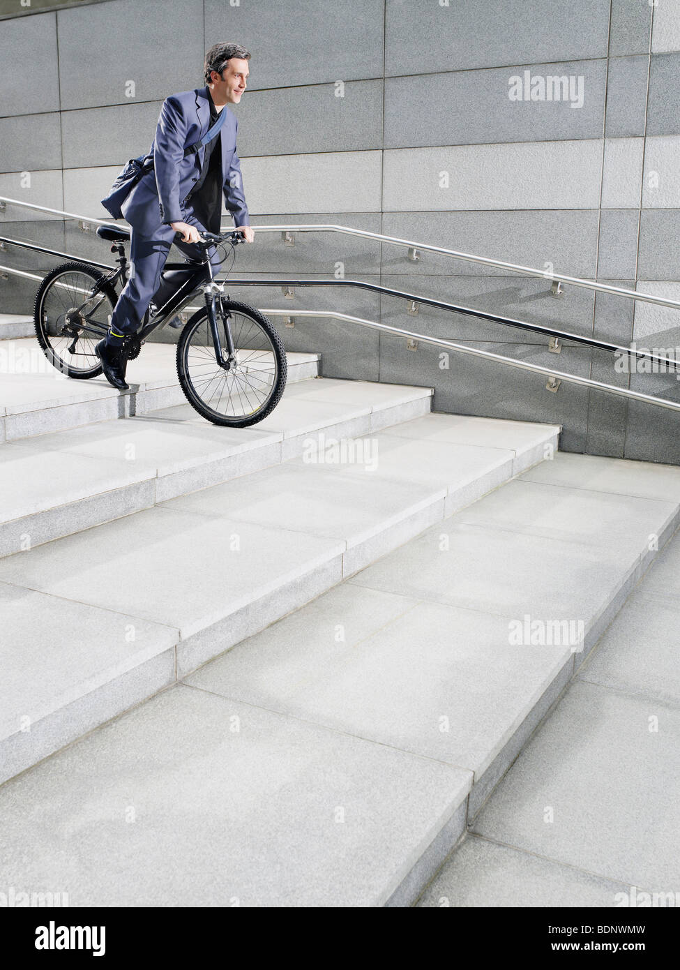 Business man riding bicycle down steps, side view Stock Photo - Alamy