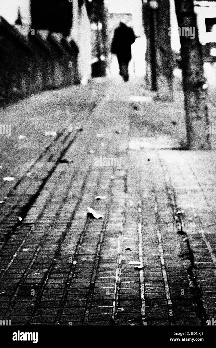 A figure walking into the distance on a pavement Stock Photo - Alamy