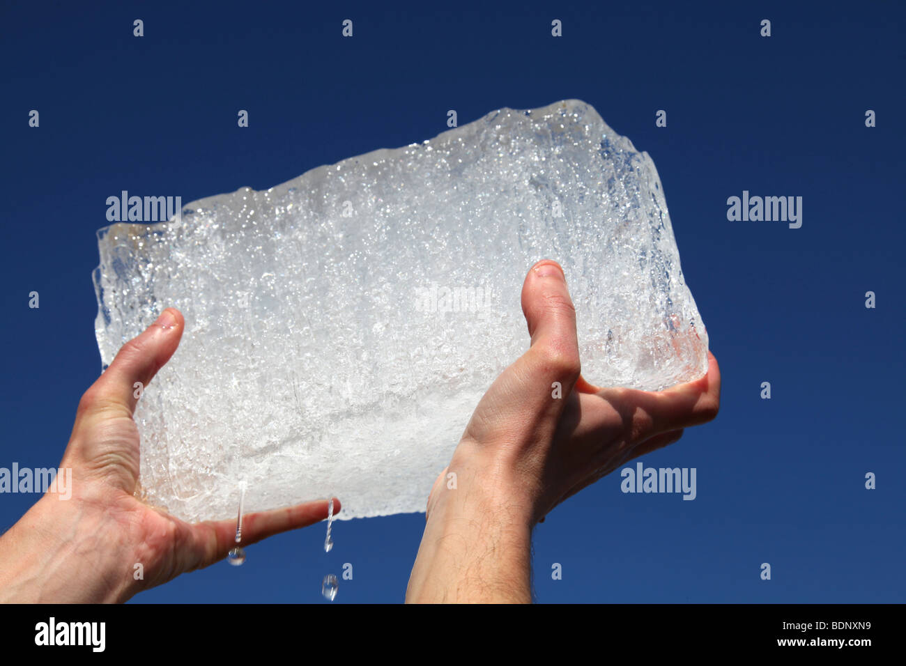 Two hands holding piece of ice Stock Photo - Alamy