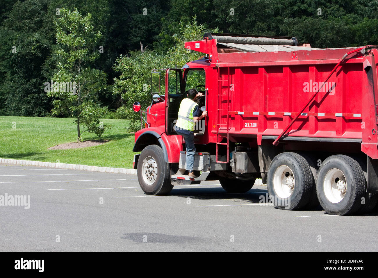 The driver is climbing into a large red dump truck lorry Stock Photo ...