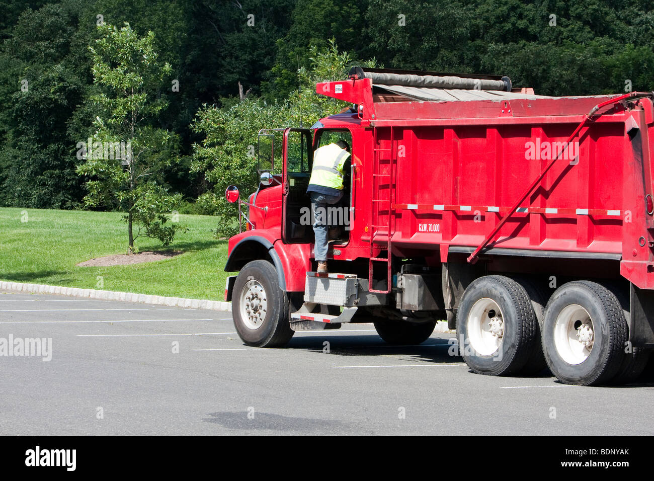 The driver is climbing into a large red dump truck lorry Stock Photo ...