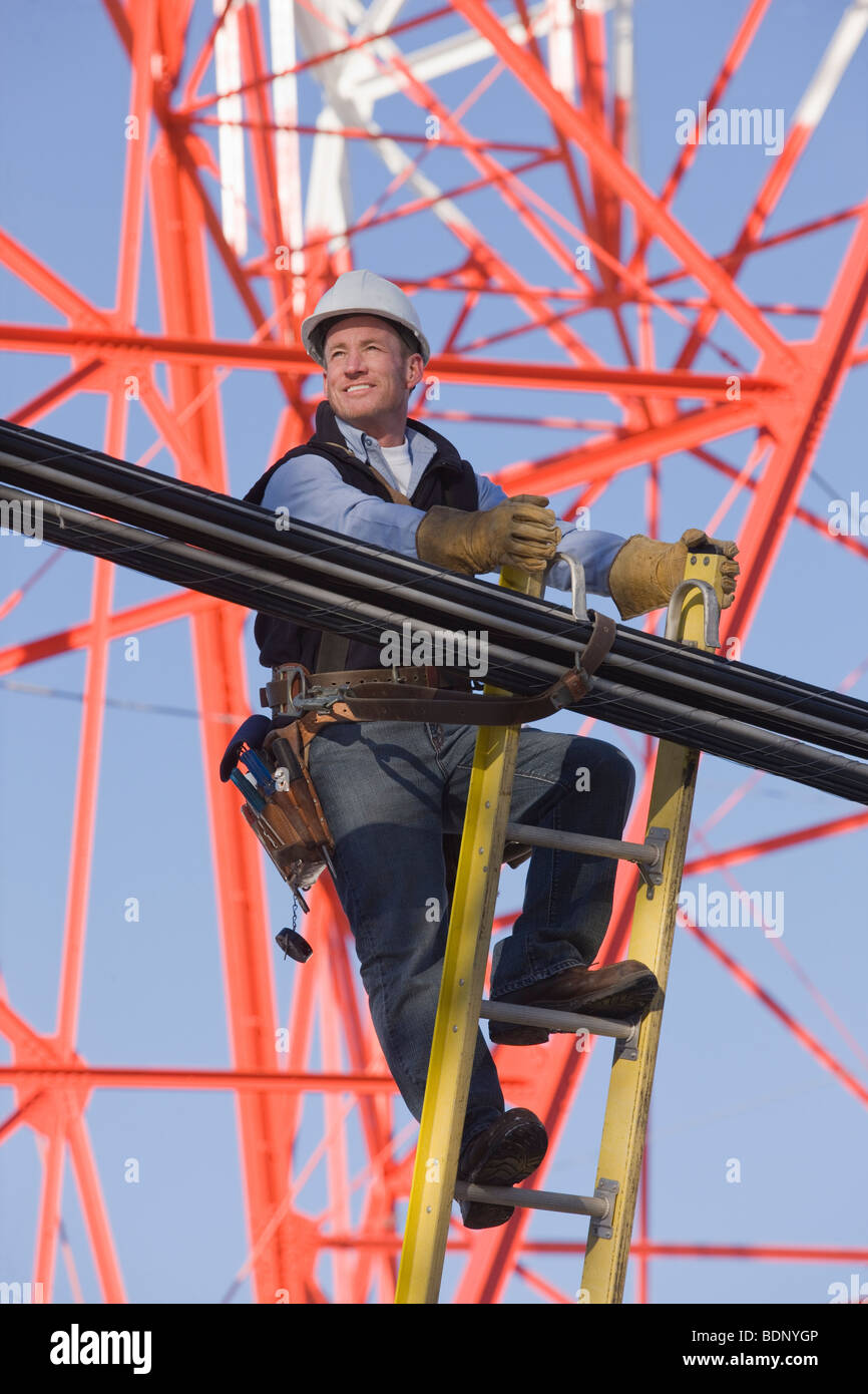 Cable lineman climbing a ladder to repair transmission line Stock Photo ...