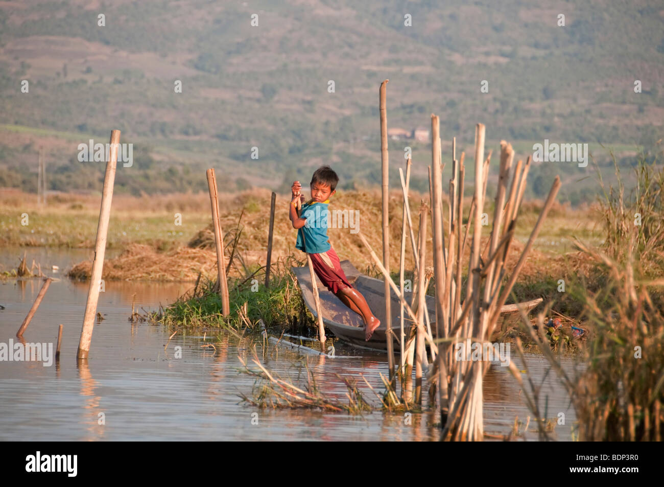 Young Shan boy taking a break from practicing one-legged rowing to lean ...