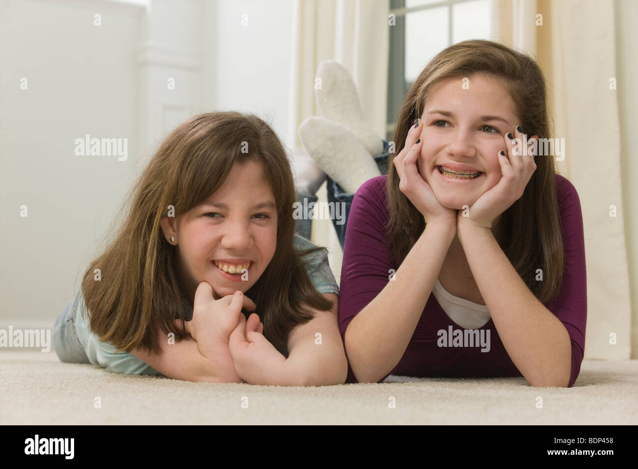 Two teenage girls lying together and smiling Stock Photo - Alamy