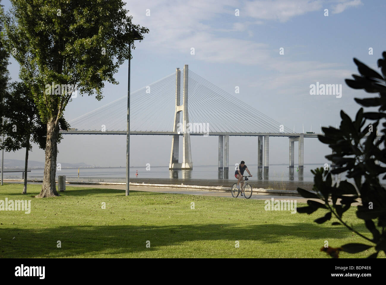 Cyclists in front of the Vasco da Gama bridge over the Rio Tejo river ...