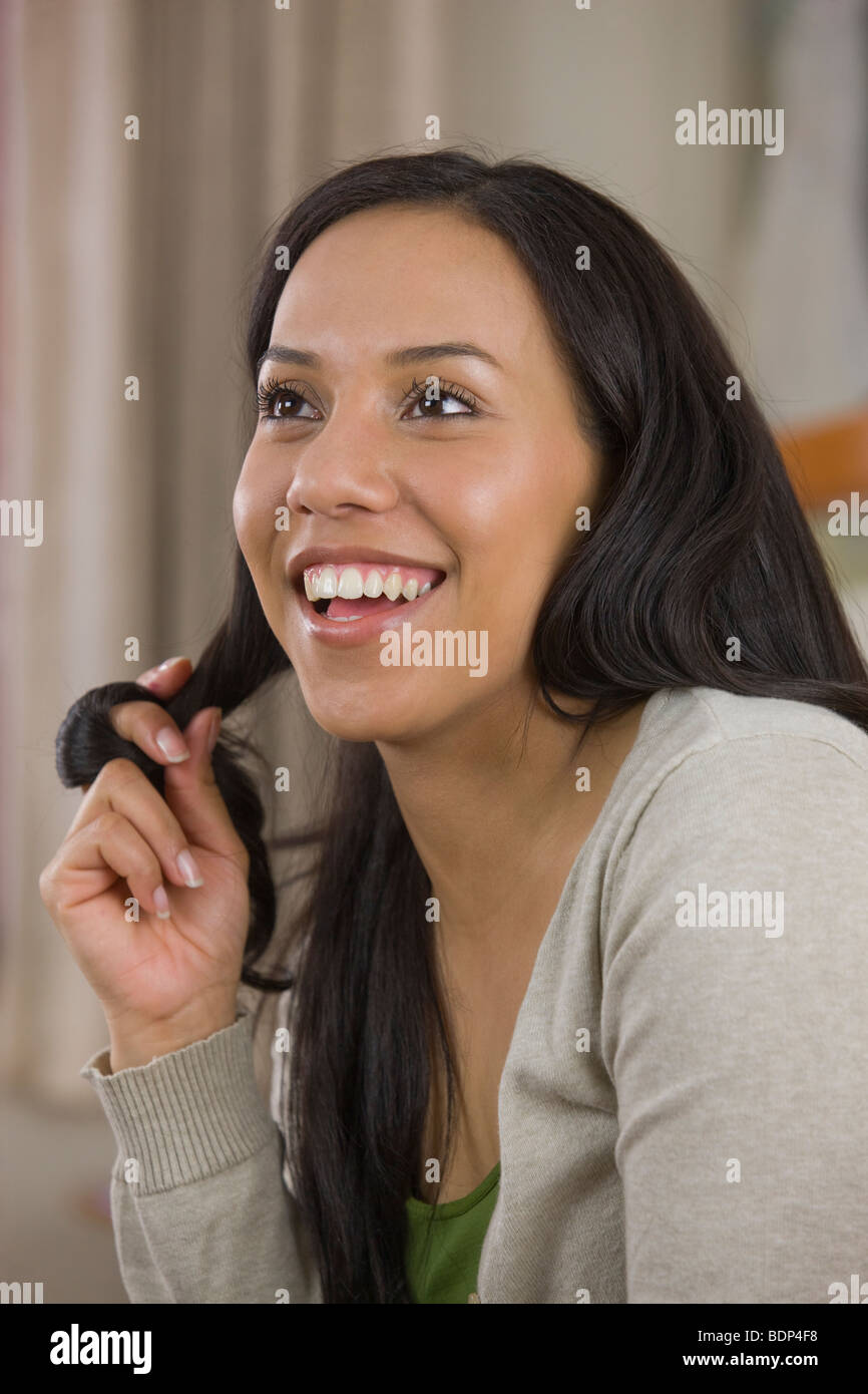 Hispanic woman twisting her hair and smiling Stock Photo - Alamy